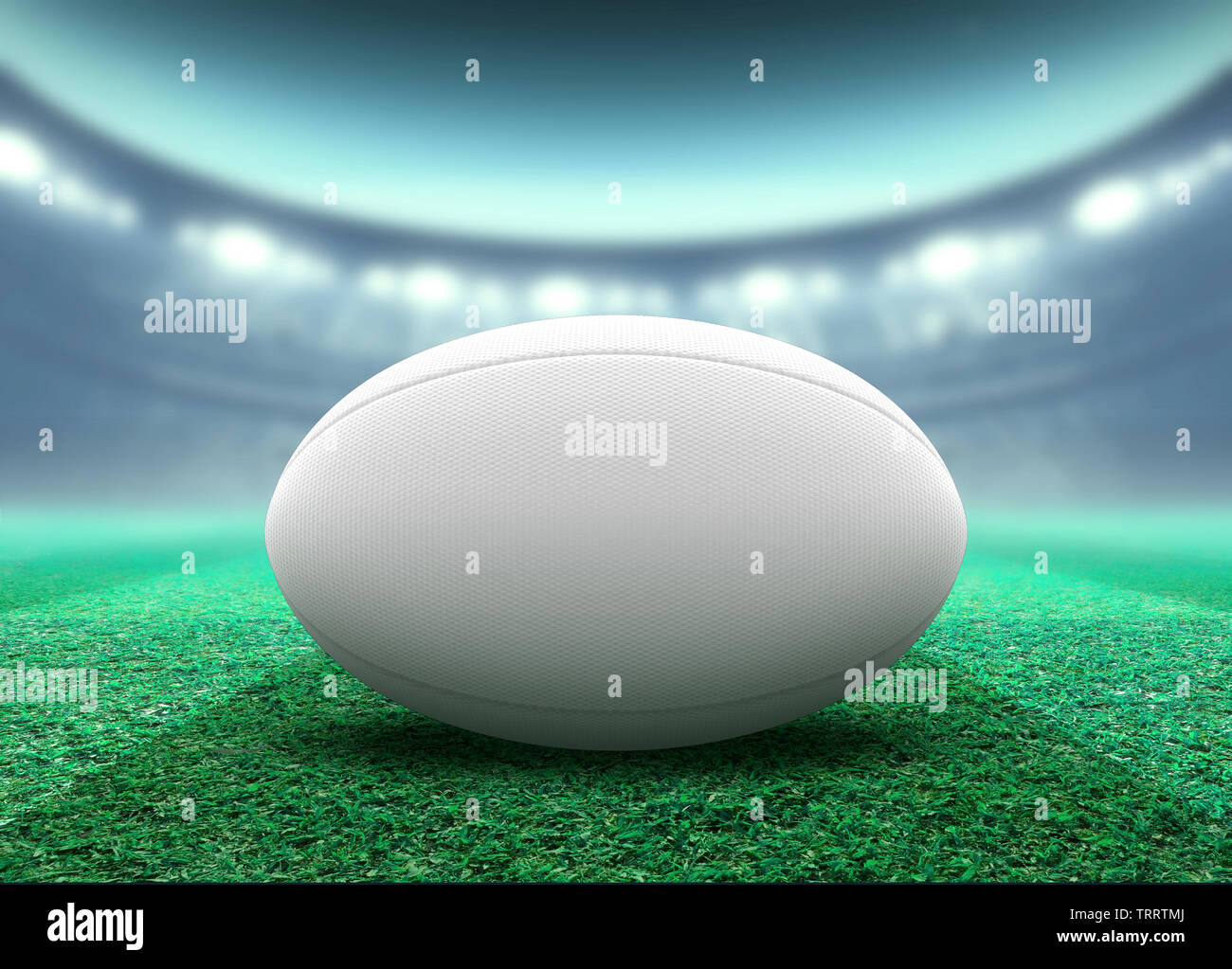 A reguar white rugby ball resting on a stadium grass pitch at night ...