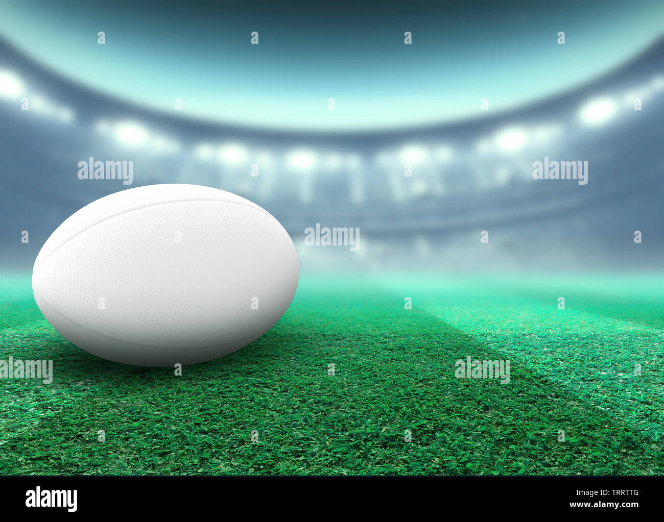 A reguar white rugby ball resting on a stadium grass pitch at night ...