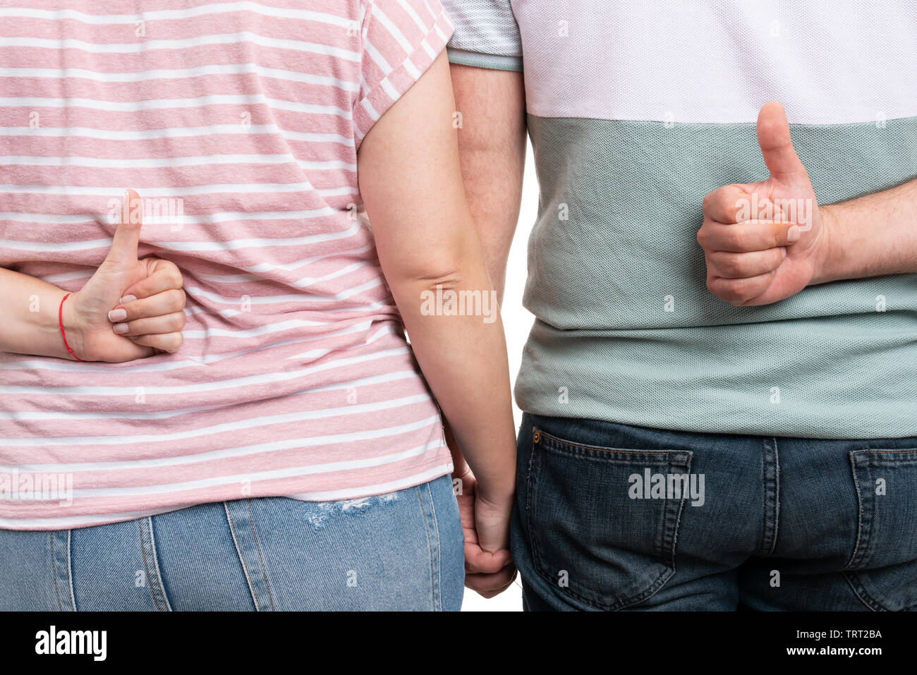 Closeup of couple showing thumbs up as agree gesture behind back ...