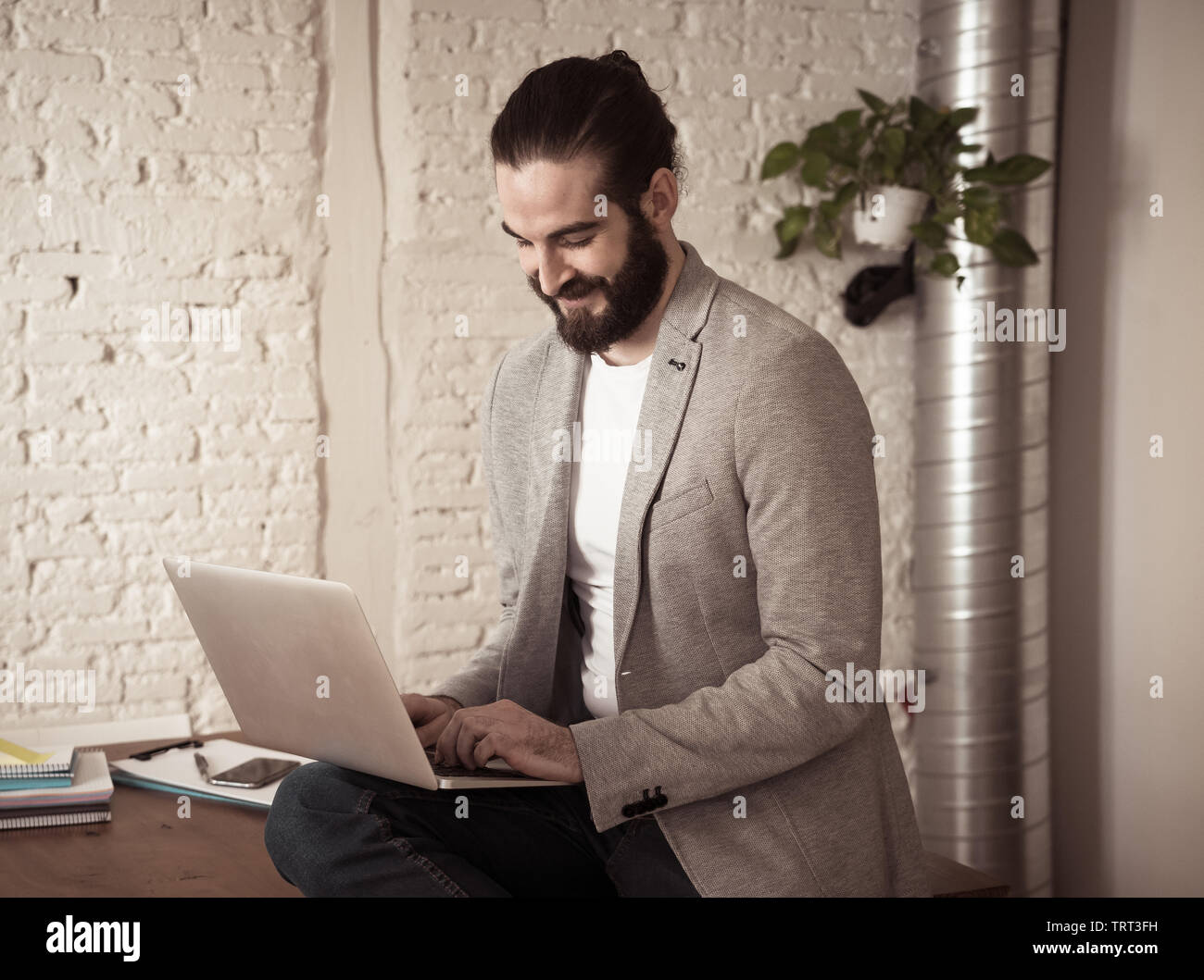 Successful hipster entrepreneur working on laptop in his modern studio ...