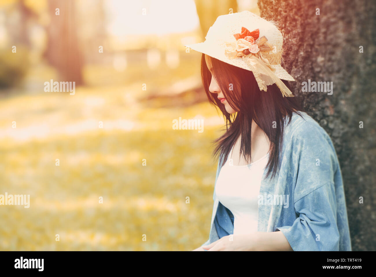 Beautiful girl sitting under the tree alone in the park outdoor summer ...