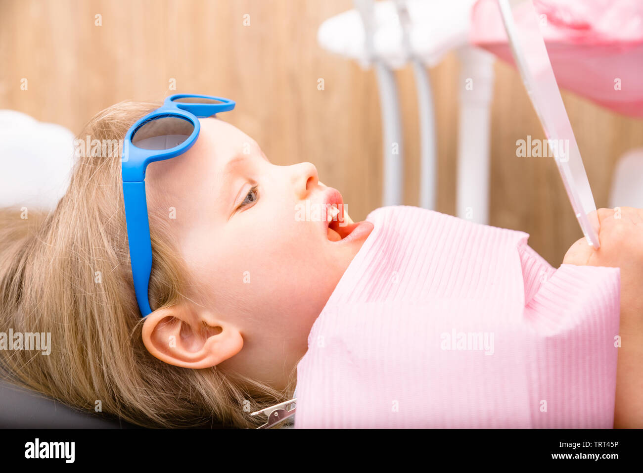 Little girl sitting in a dental chair inspecting her cured teeth ...