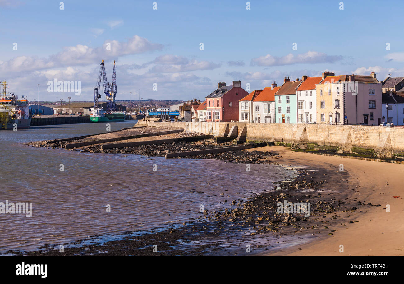 The beach,sea walls and houses with the cranes in the background at the ...