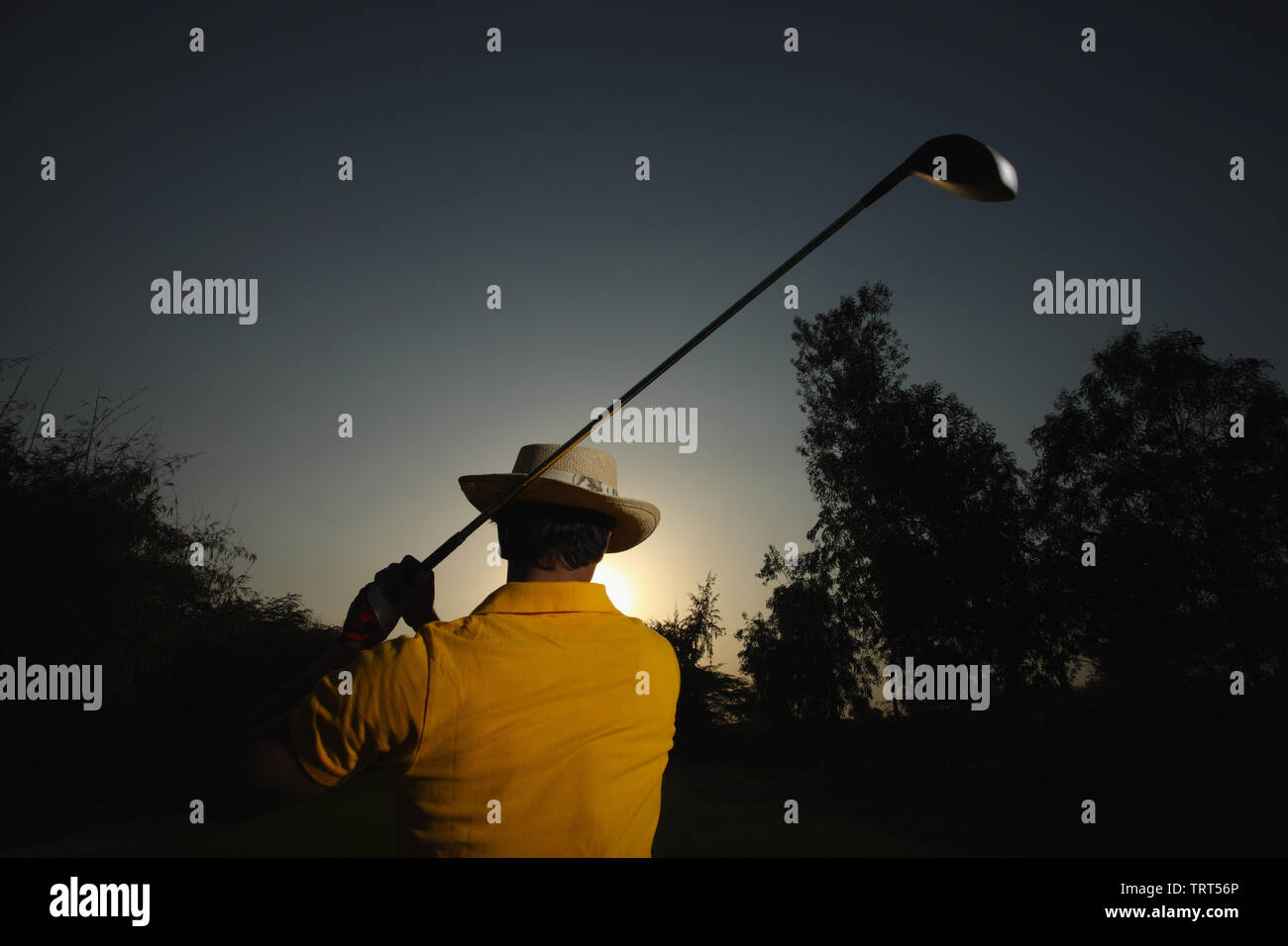 Rear view of a man swinging a golf club Stock Photo - Alamy
