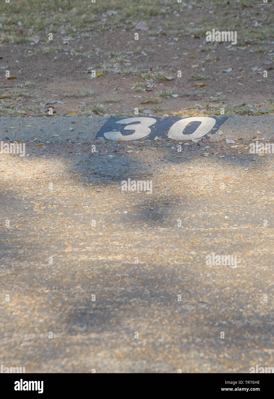 Street number thirty painted onto a curb stone has faded over time ...