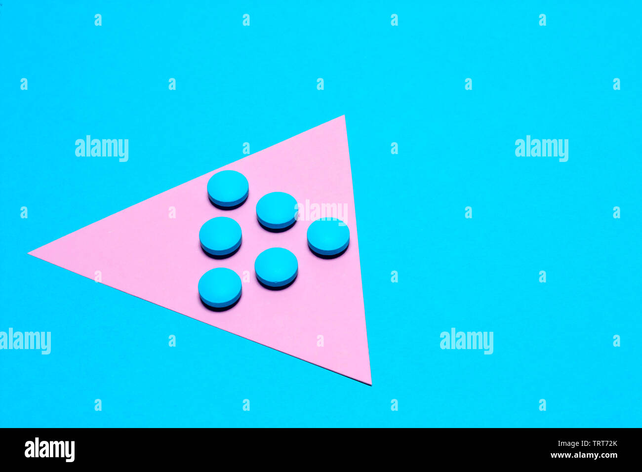 blue tablets laid out in the form of a triangle or an arrow on a paper ...