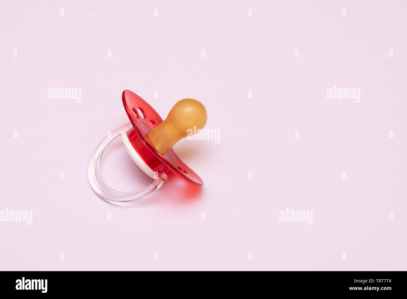 Baby red pacifier on pink background Stock Photo - Alamy