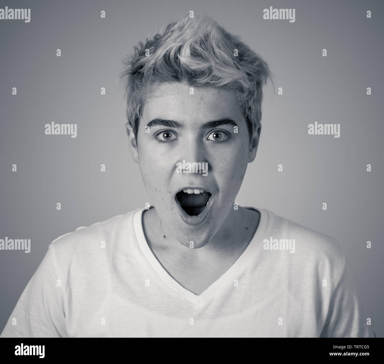 Handsome young blonde teenager boy with happy face making surprised ...