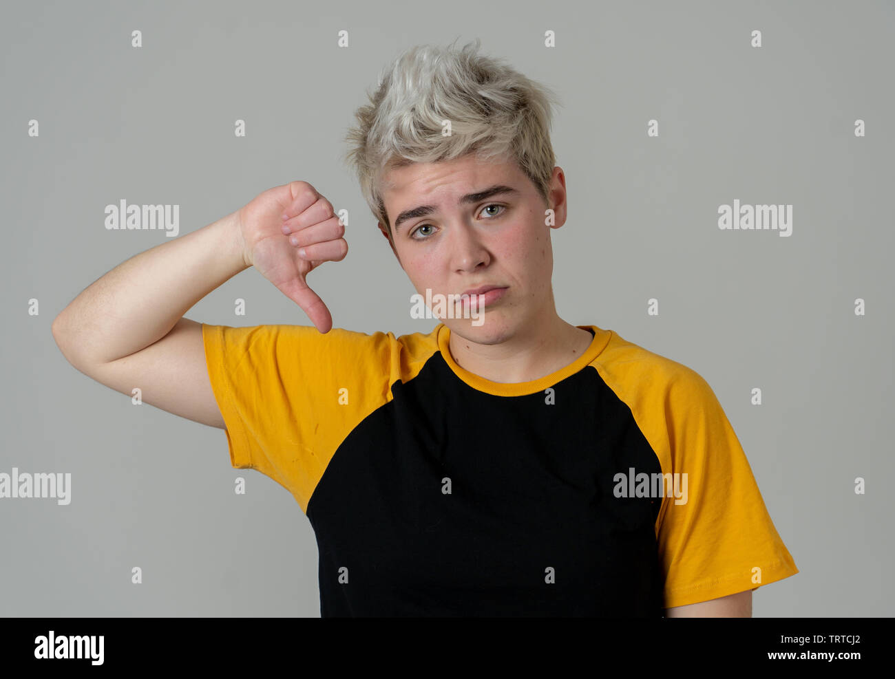 Portrait of young good looking teenager boy making thumbs down feeling ...