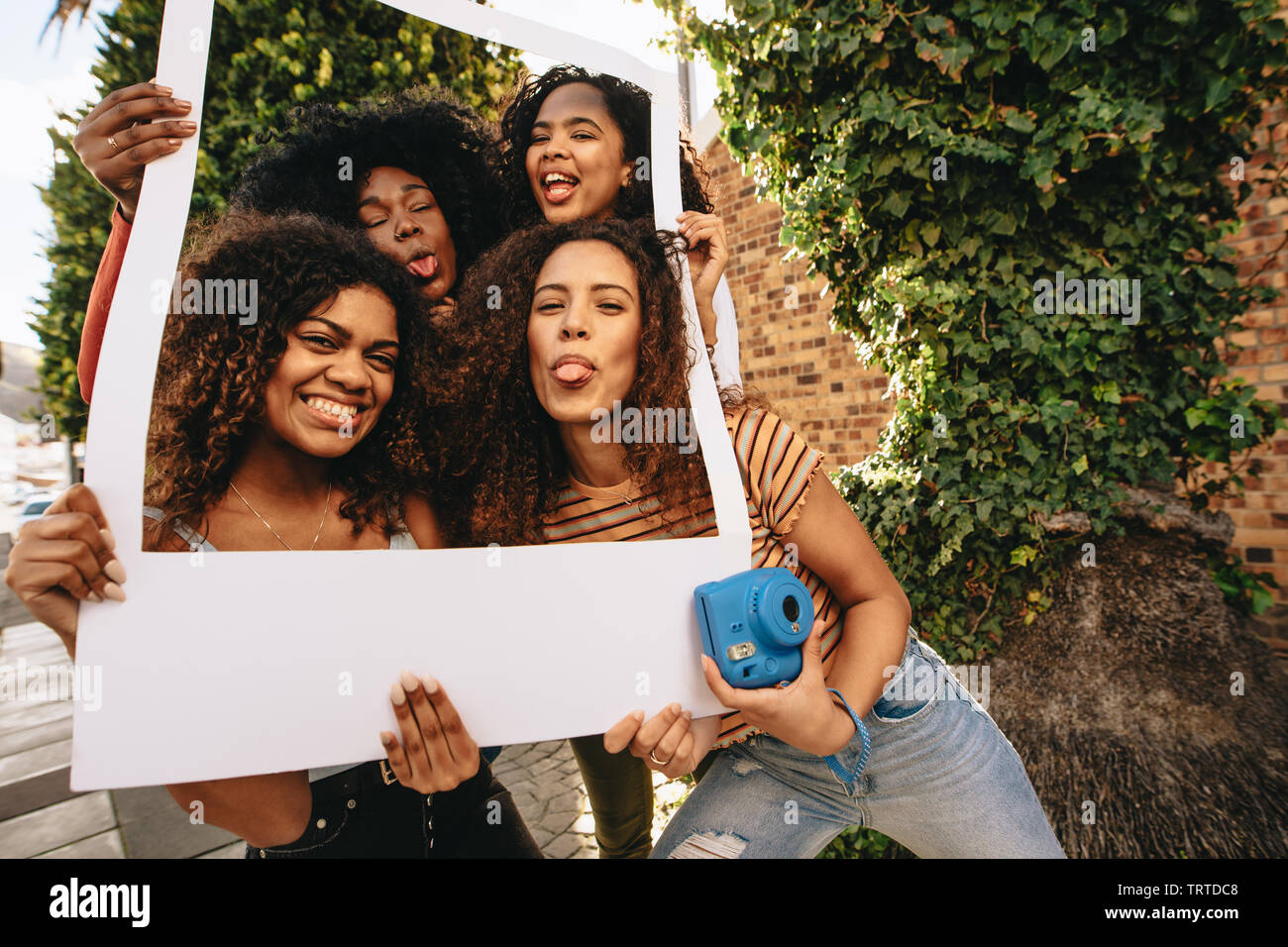 Group of women with blank picture frame. Girls making funny faces with ...
