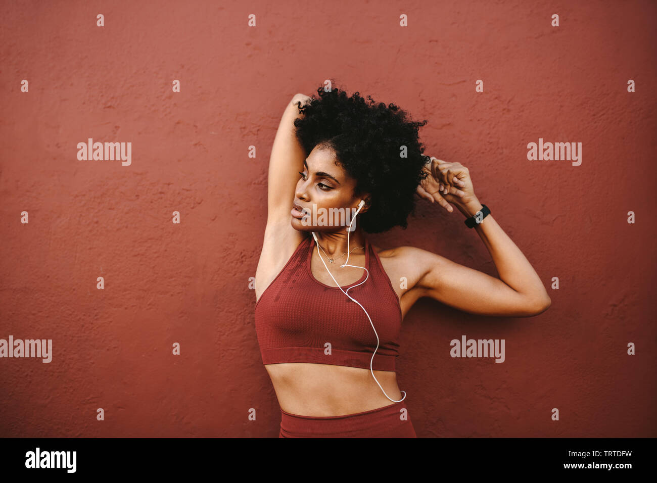 Healthy and fit woman standing by a wall outdoors. Female taking a rest ...