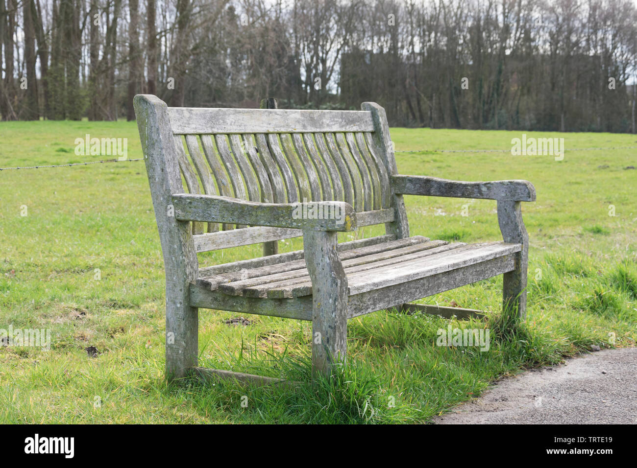 Old bench on the edge of a field with trees in the background Stock ...