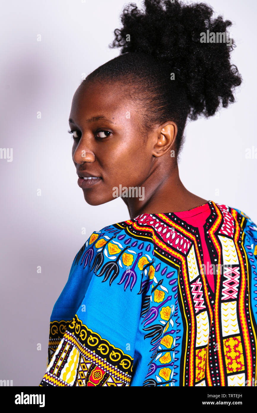 Portrait of young african girl in blue dress turned back and looking at ...