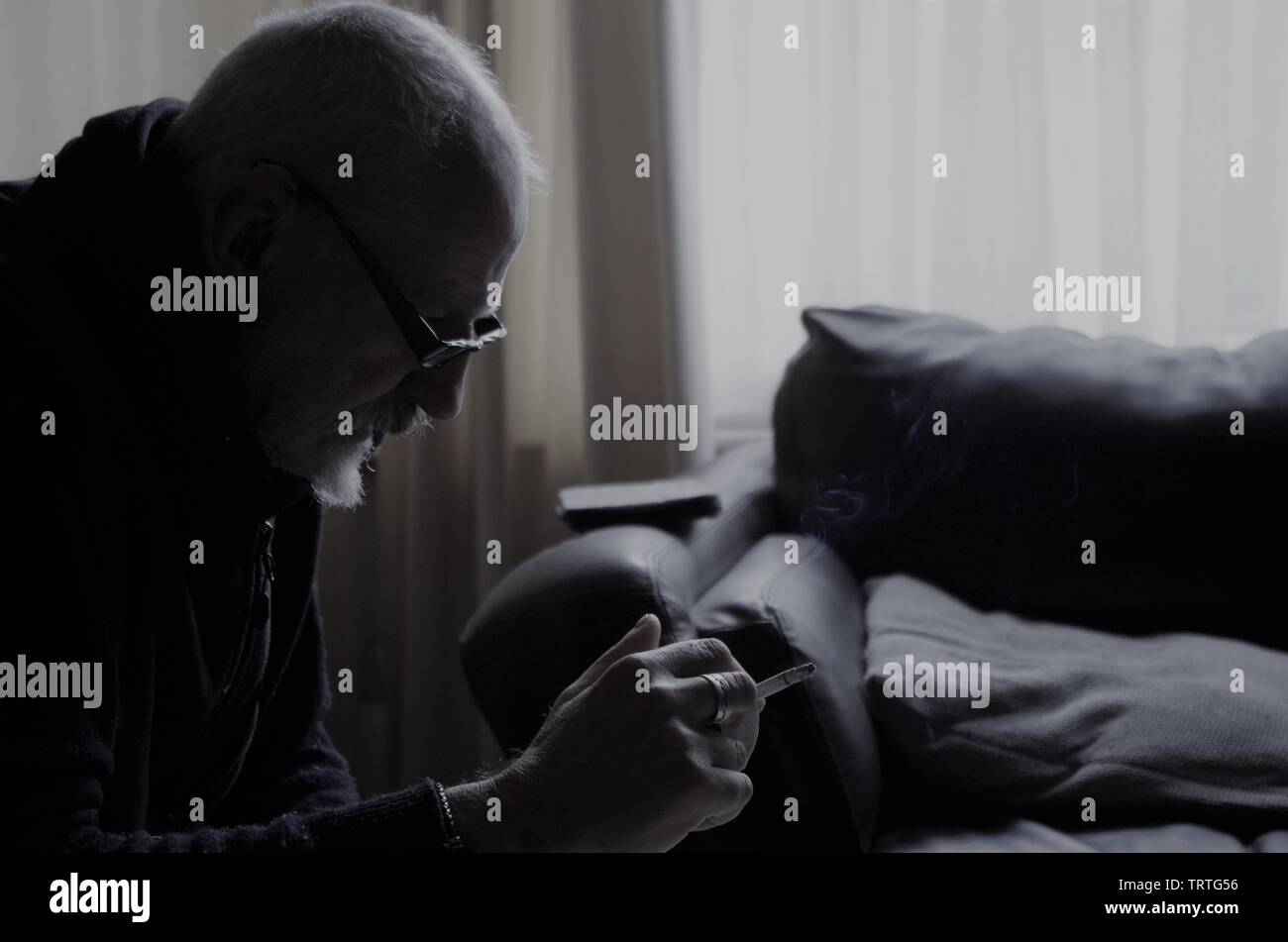 Man smoking cigarette inside home Stock Photo - Alamy