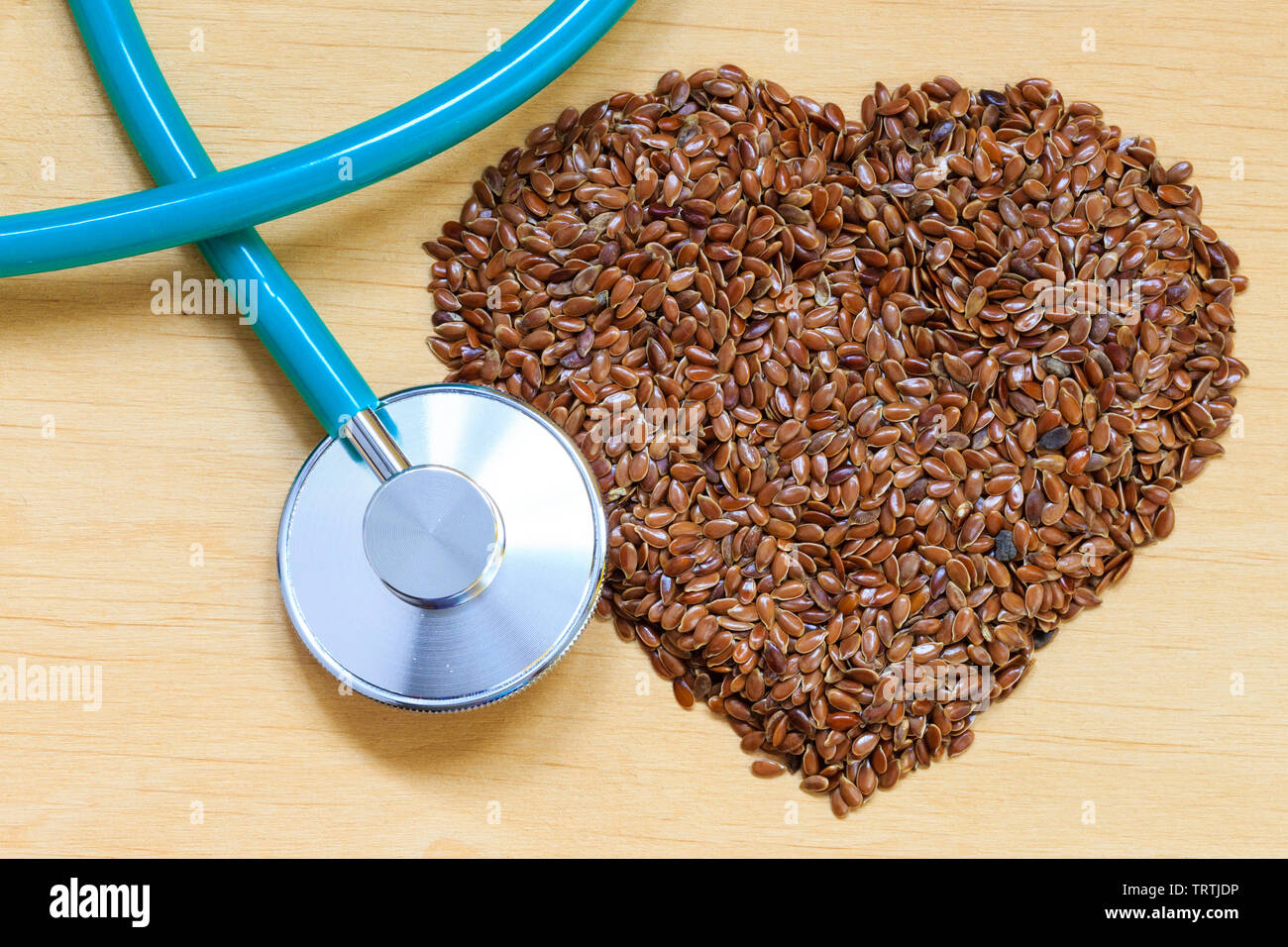 Diet healthcare and checkup concept. Raw flax seeds linseed heart shaped and stethoscope ...