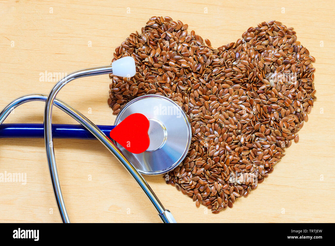 Diet healthcare and checkup concept. Raw flax seeds linseed heart shaped and stethoscope ...