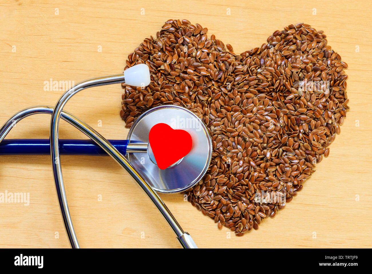 Diet healthcare and checkup concept. Raw flax seeds linseed heart shaped and stethoscope ...