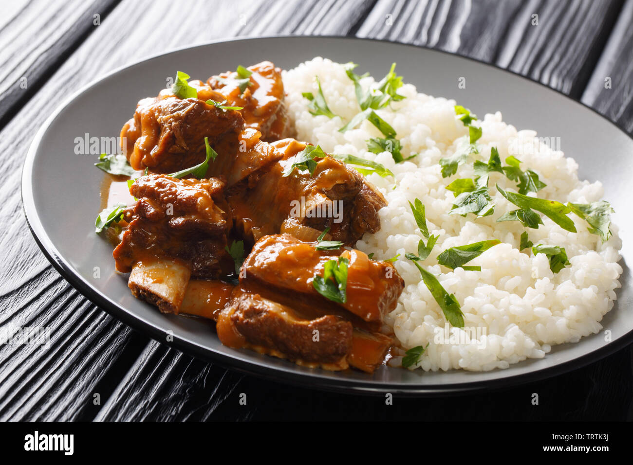 short ribs cooked in a spicy sauce with rice garnish close-up on a ...