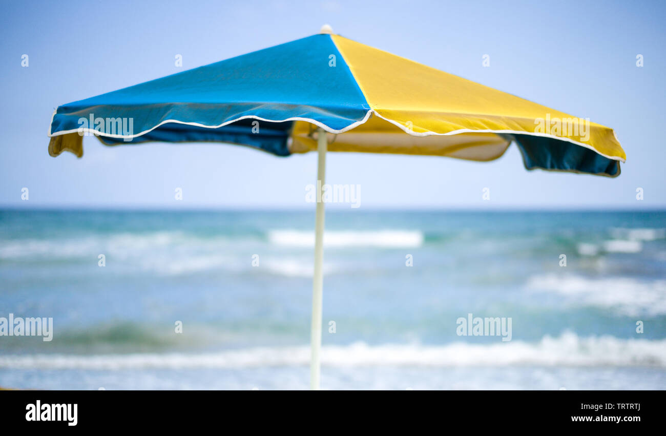 Blue and yellow beach umbrella with stunning backdrop of the sea waves ...