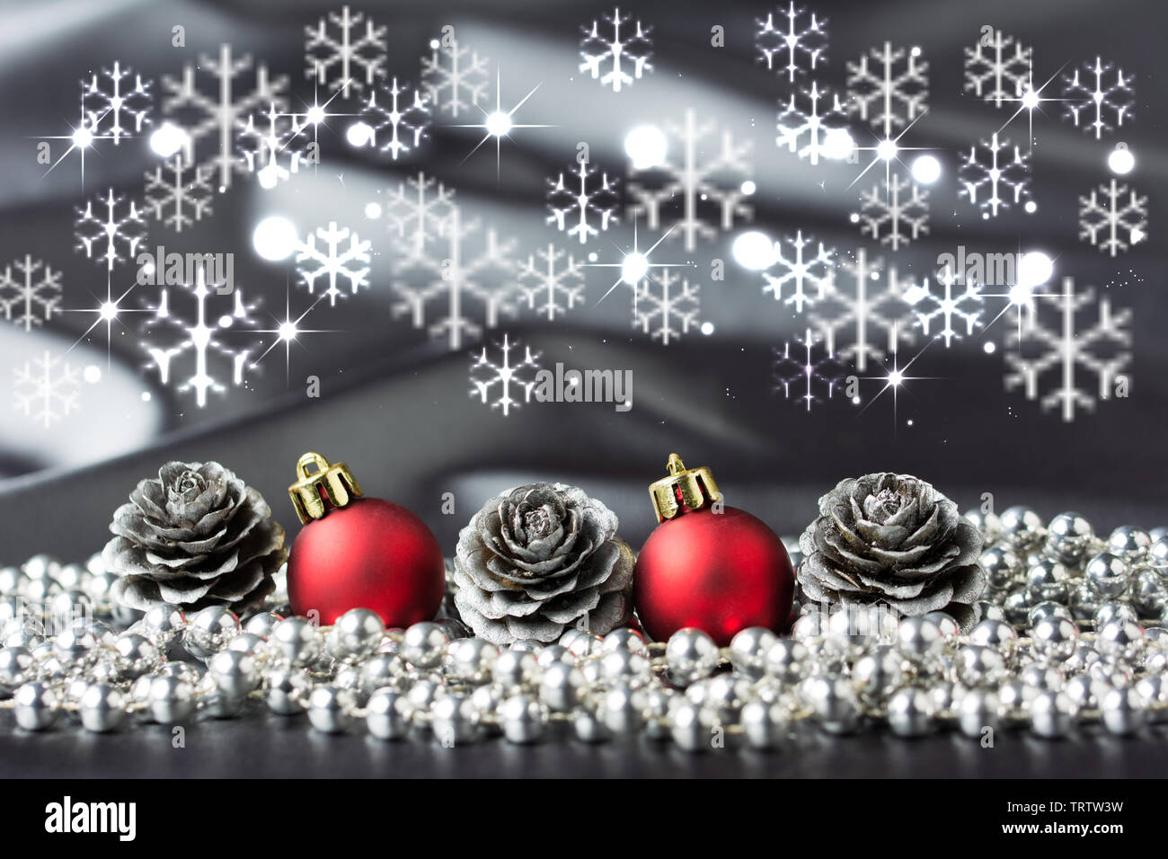 Three silver cones, two red baubles and bead chain on grey cloth ...