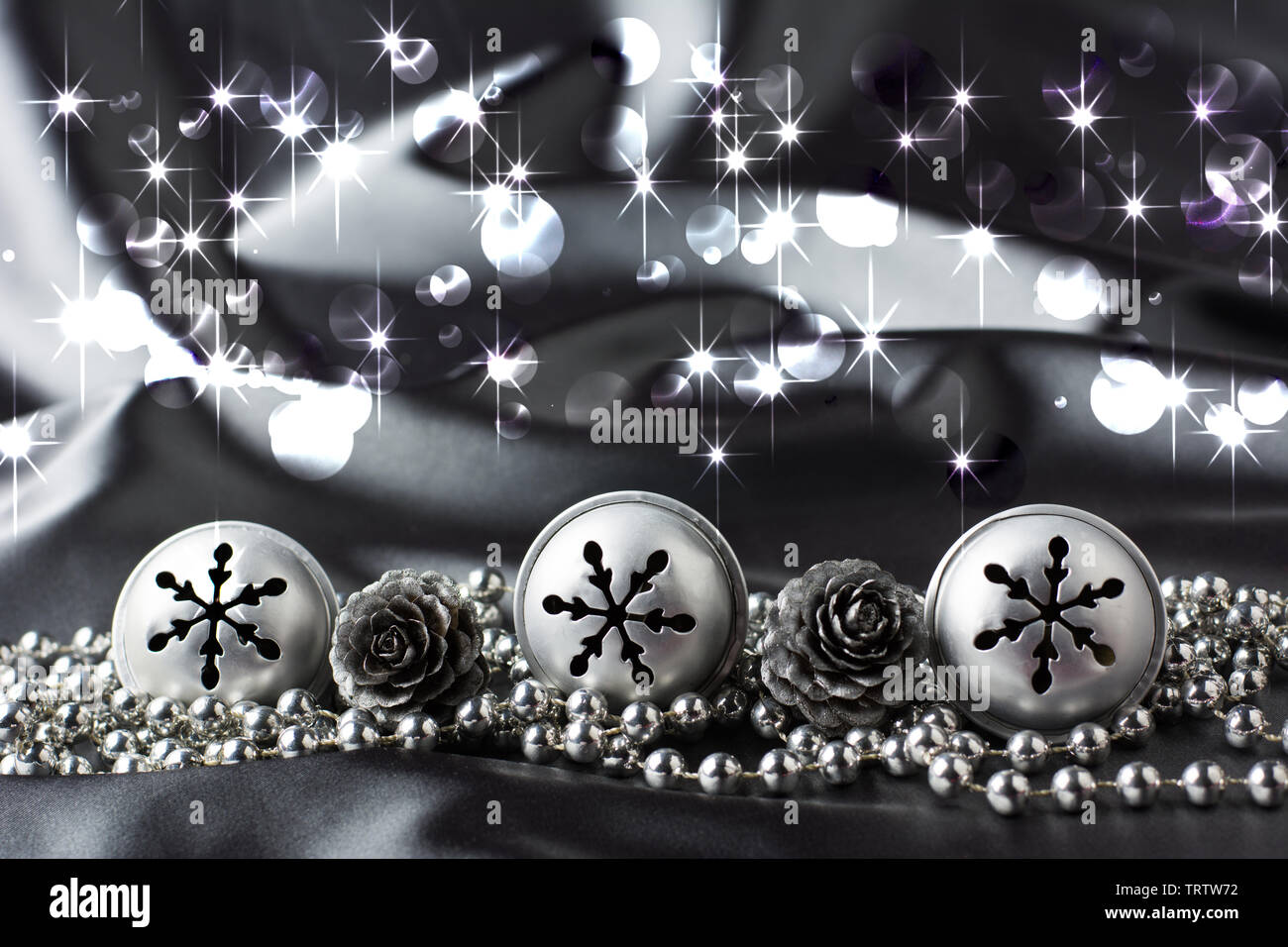 Three silver jingle bells, two silver cones and bead chain on grey ...