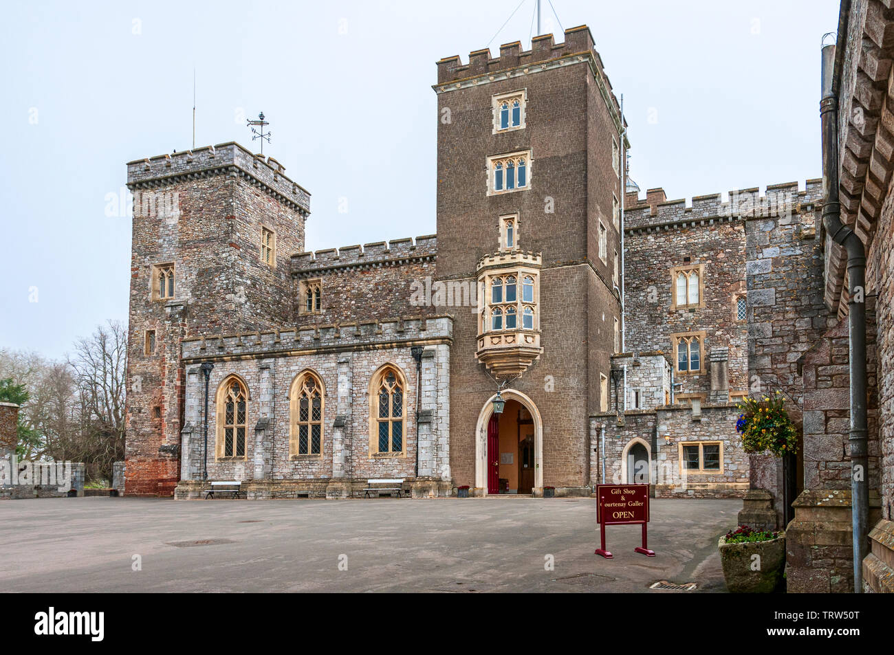 The attractive façade of medieval Powderham Castle with a central tower ...