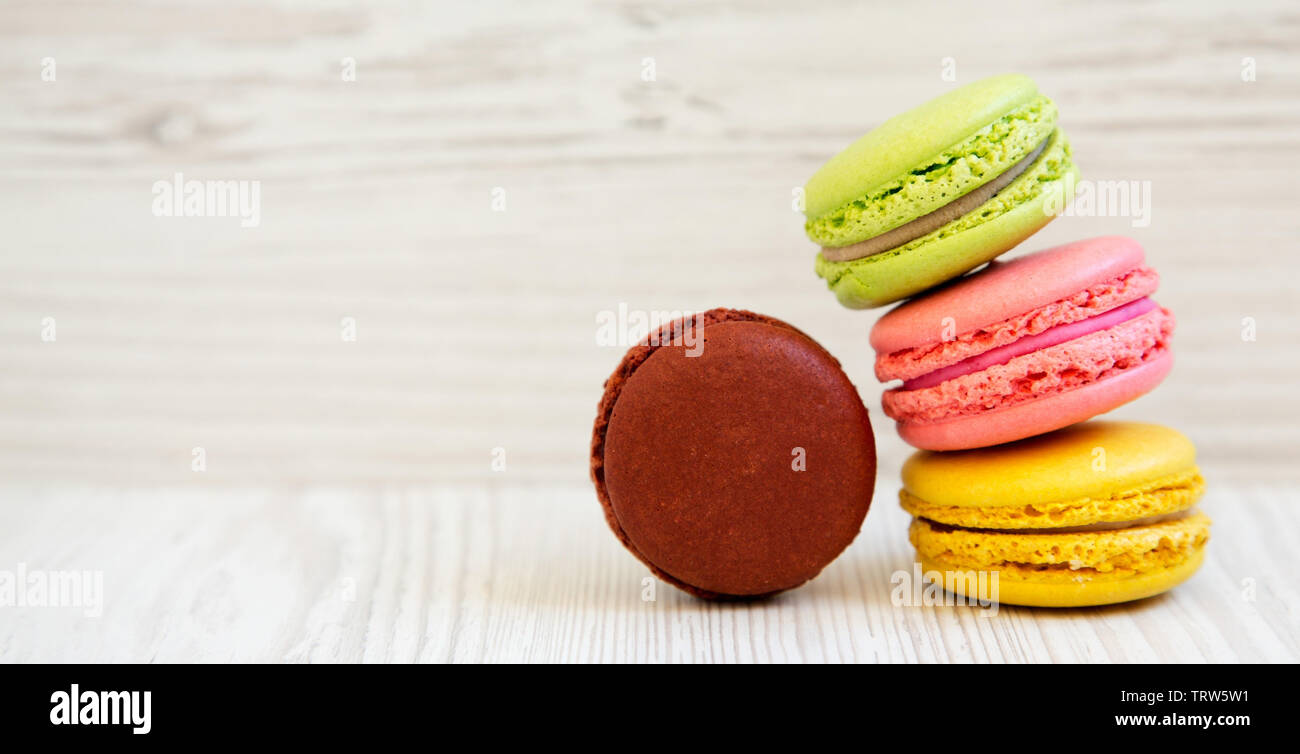 Sweet and colorful macarons on a white wooden background, side view ...