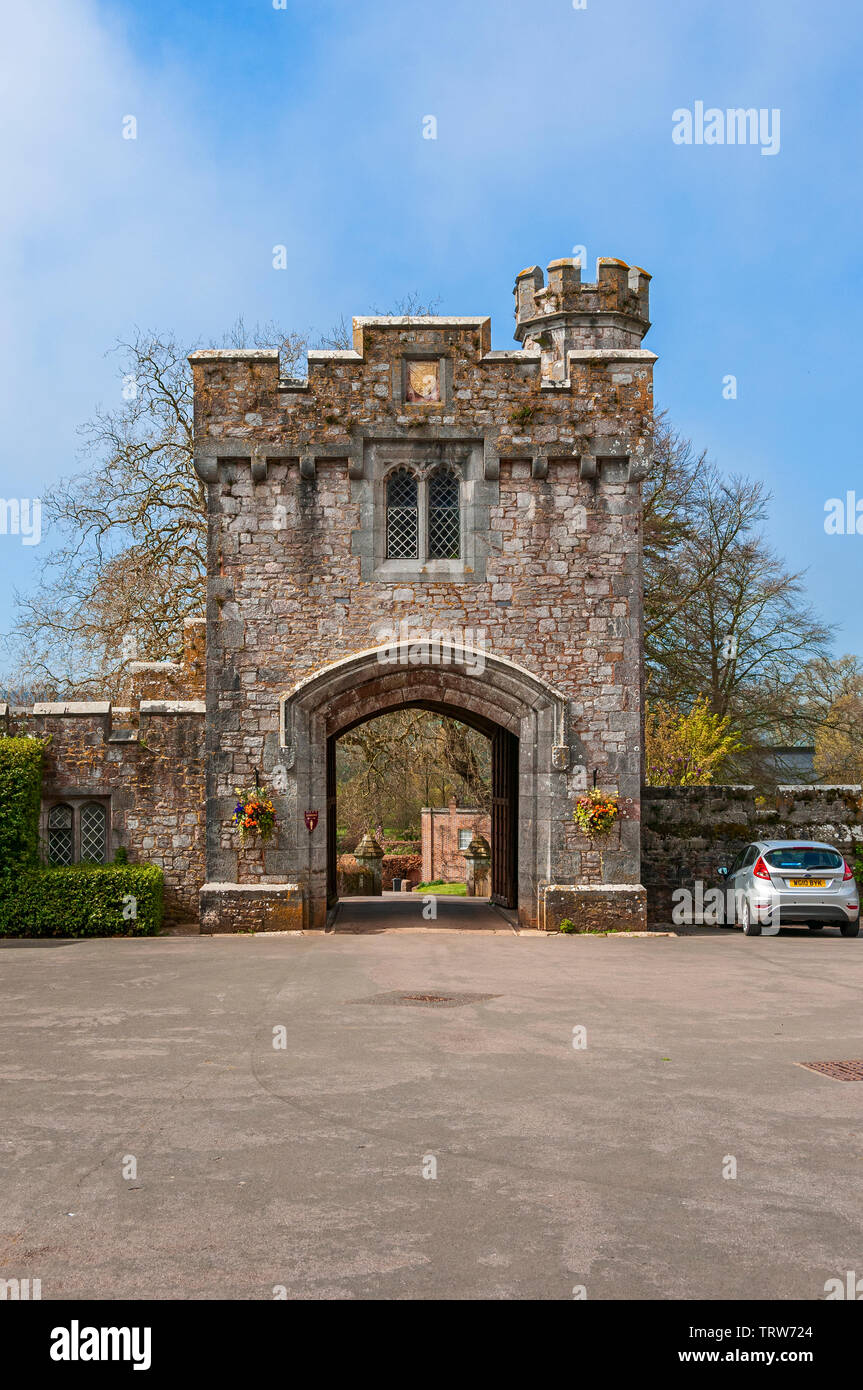 A drive leads up from attractive parkland through the archway of a two ...