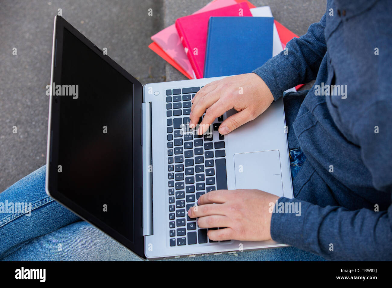 Students using laptop and books learning for the exam on campus stairs ...