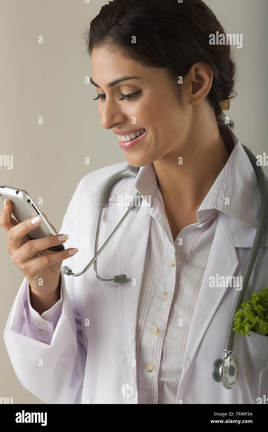 Female doctor text messaging and smiling Stock Photo - Alamy