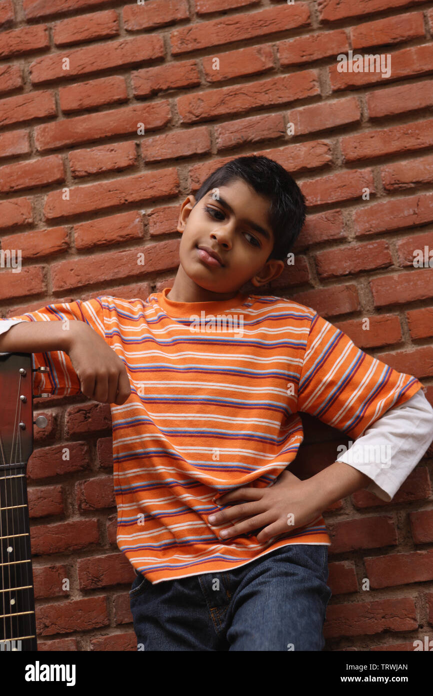 Boy leaning against a wall with a guitar Stock Photo - Alamy