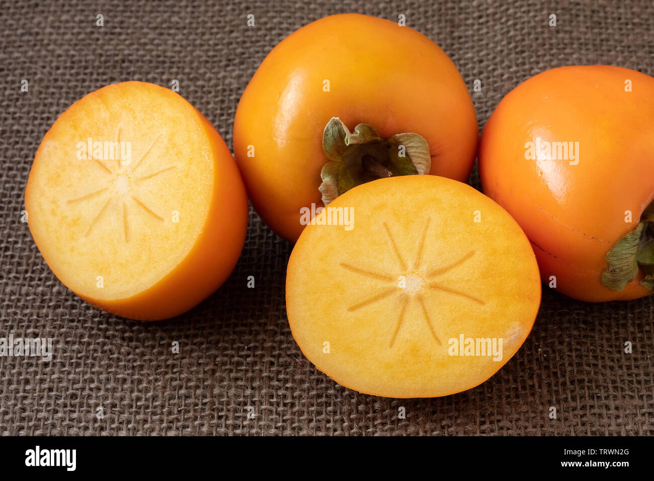 Whole and half of fresh ripe persimmons. Japanese persimmon (Diospyros ...