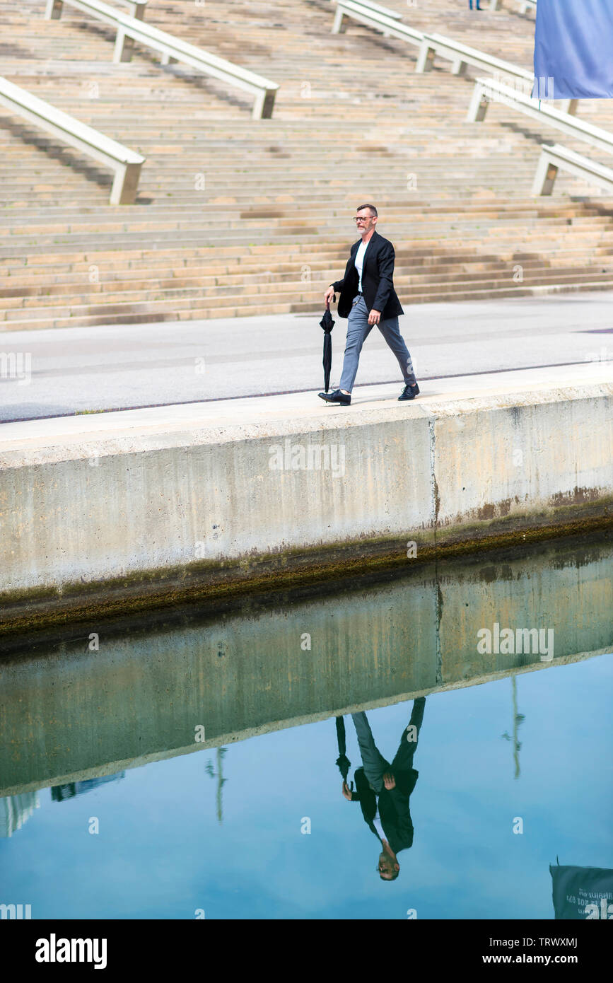 Adult man in formal clothes while walking on promenade holding an ...