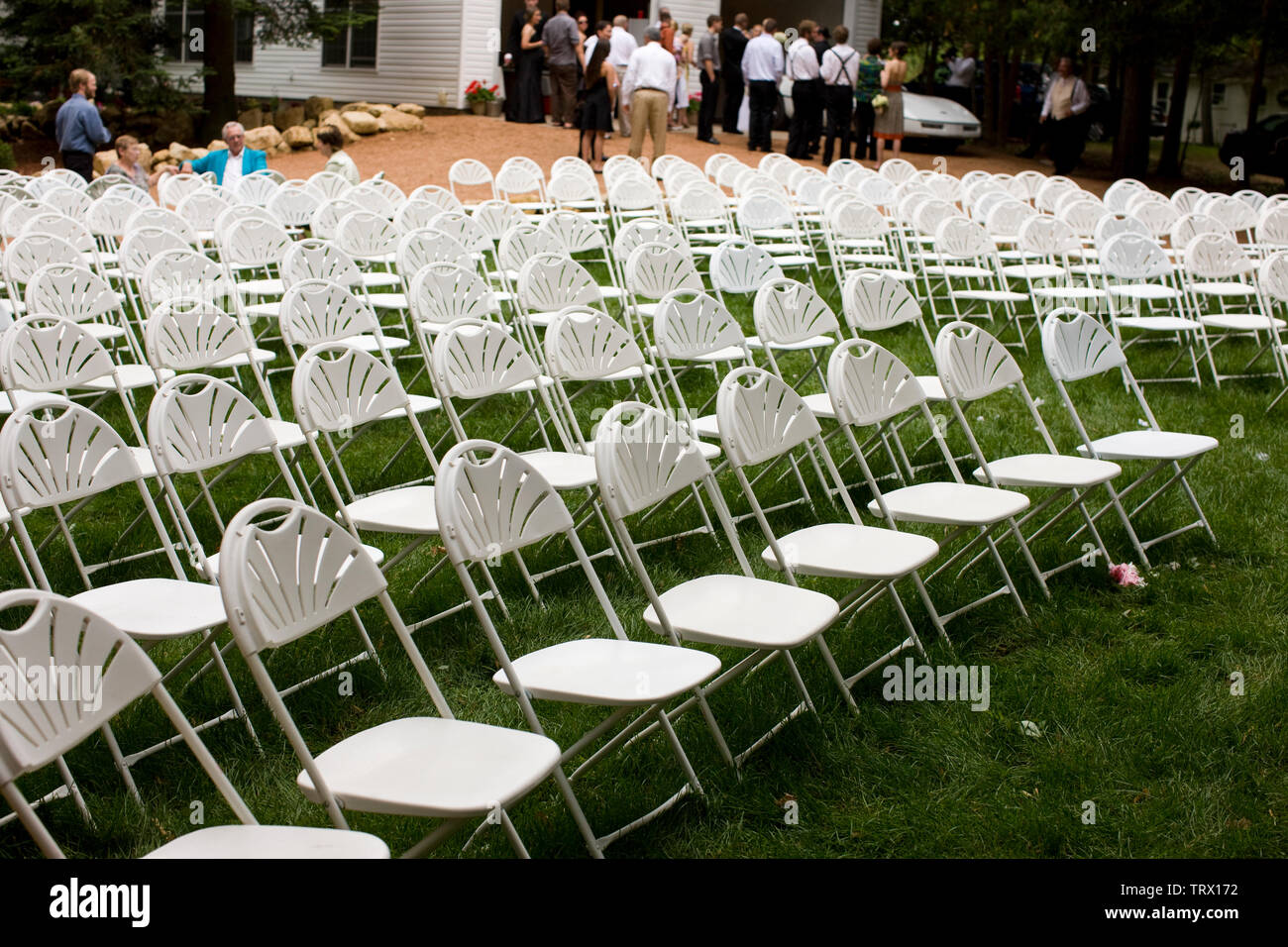 Rows of empty white folding chairs in a backyard Stock Photo - Alamy