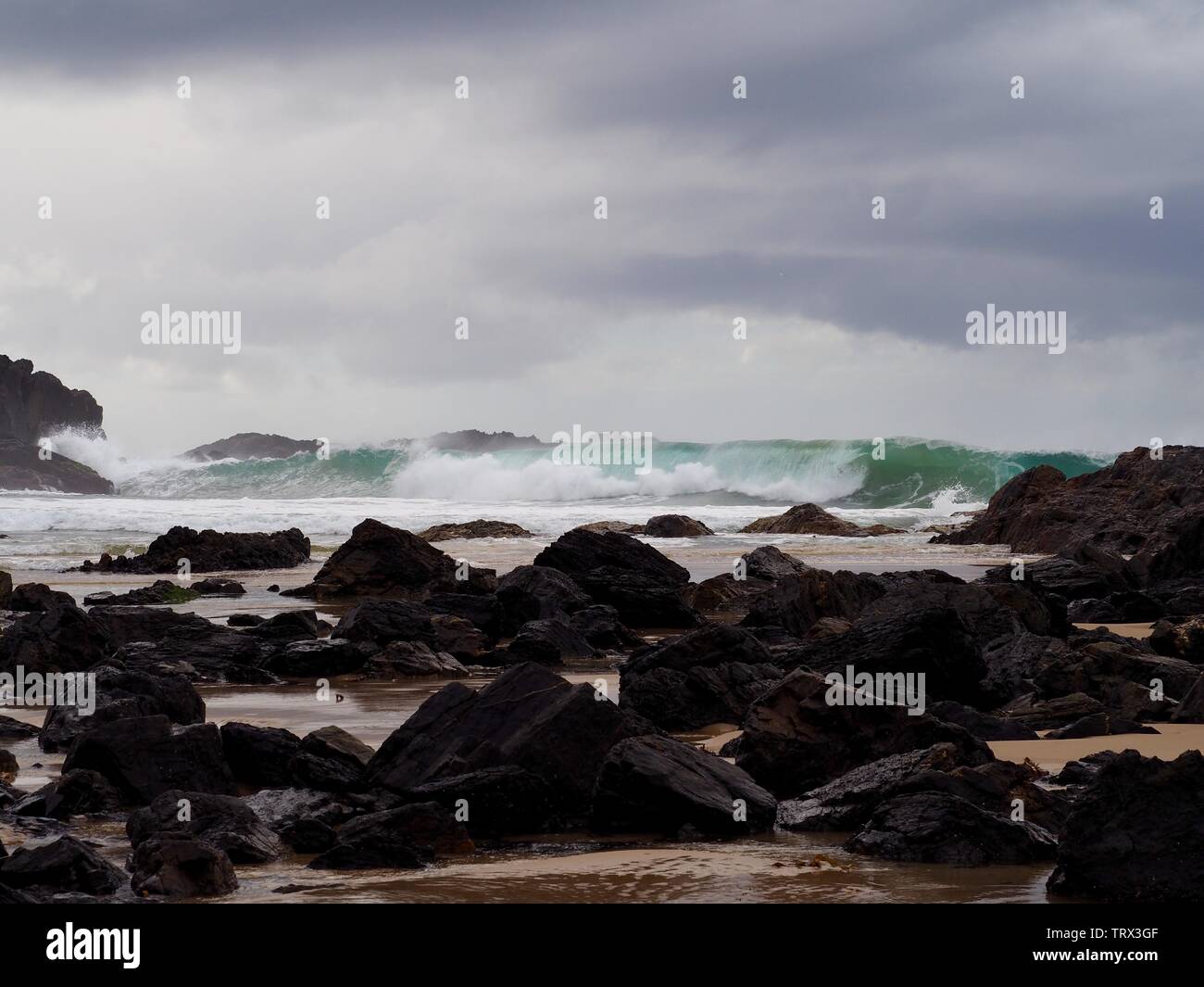 Wild stormy weather at the beach, blue green waves rolling in, crashing ...