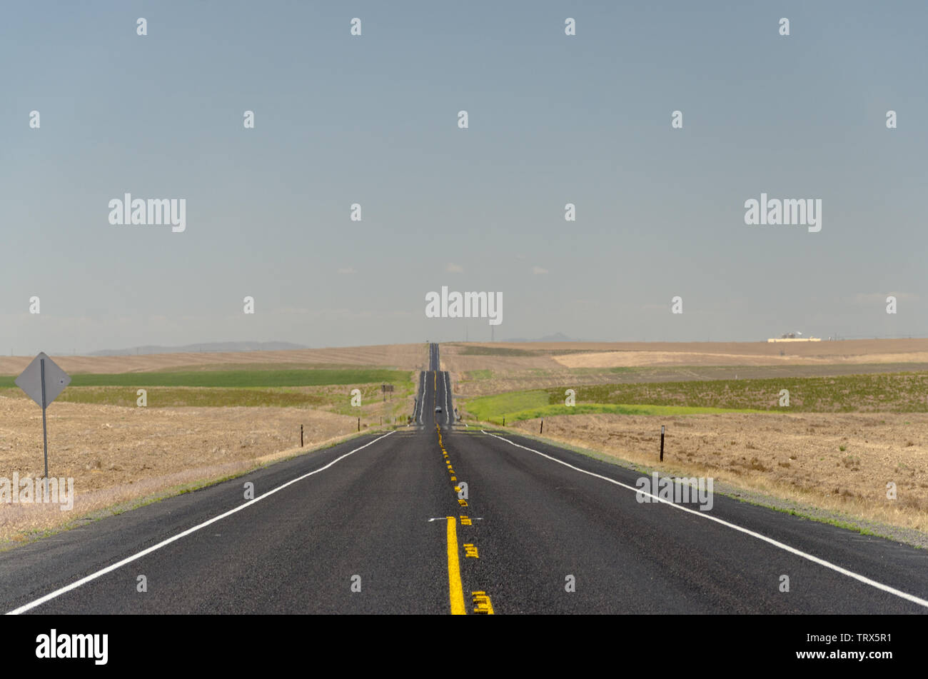 long road into the distance with farm land on each side Stock Photo - Alamy