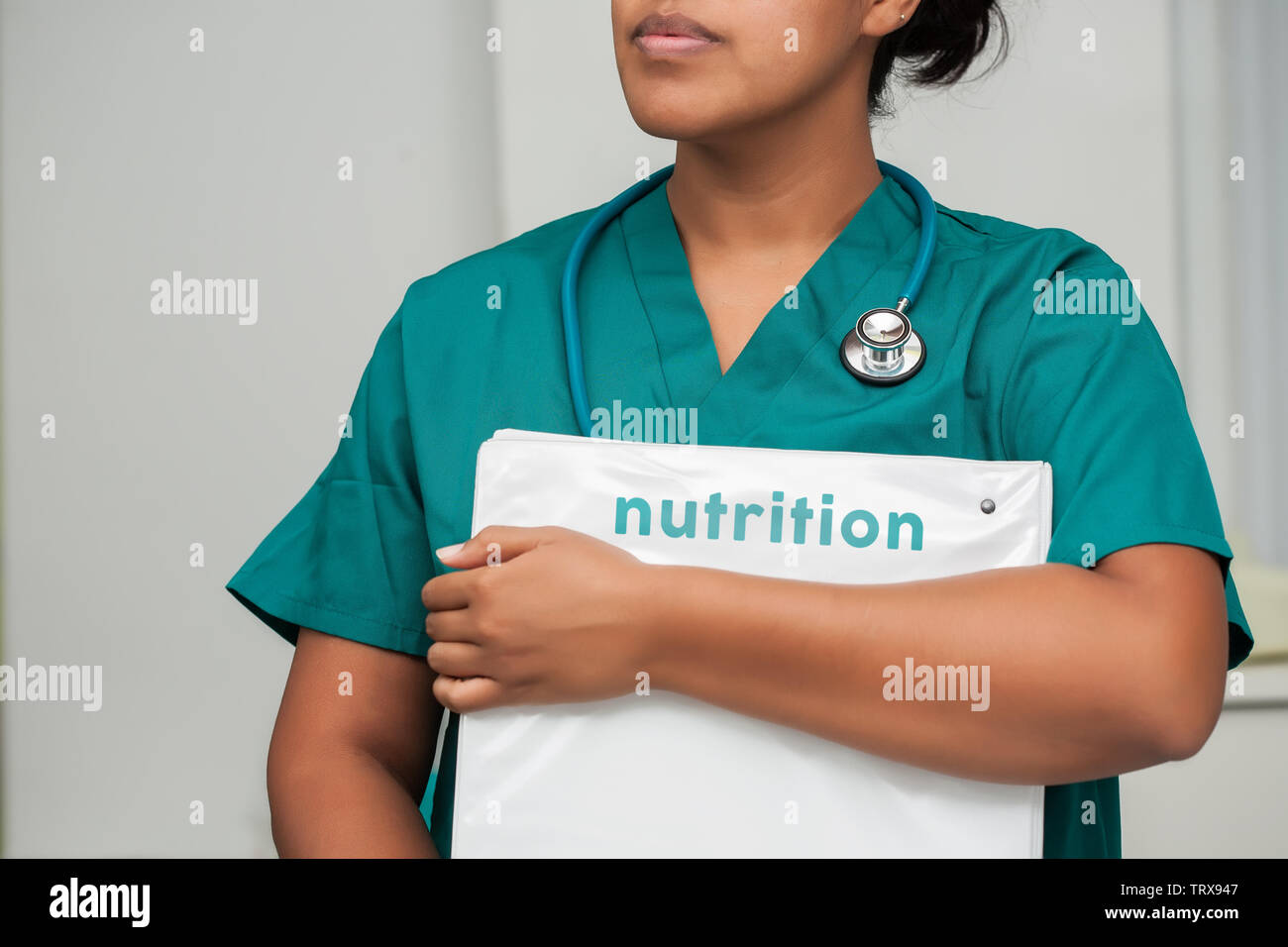 Health professional holding a nutrition binder in her arms and wearing ...