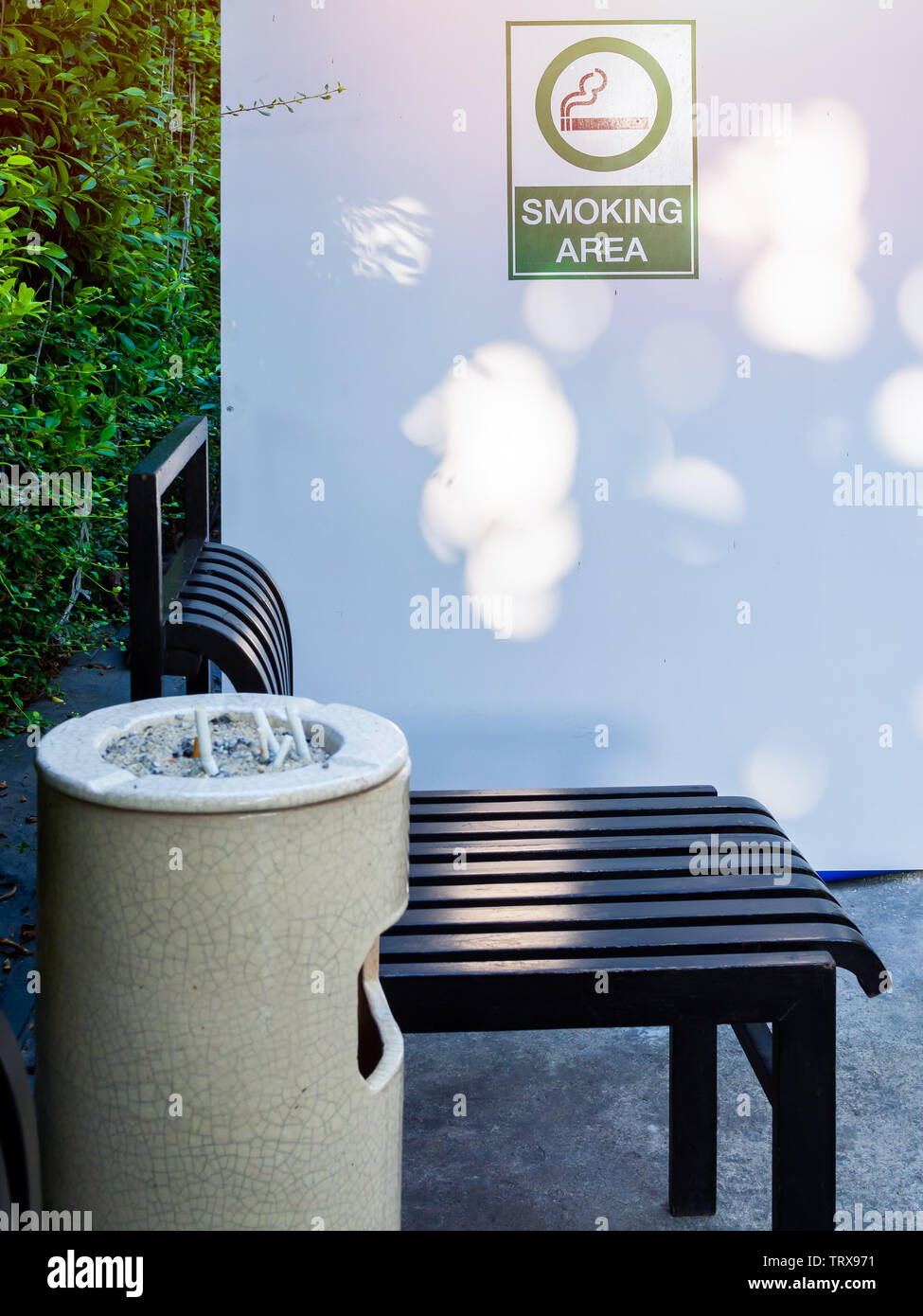 Black chairs with ashtray in smoking area on green garden background ...