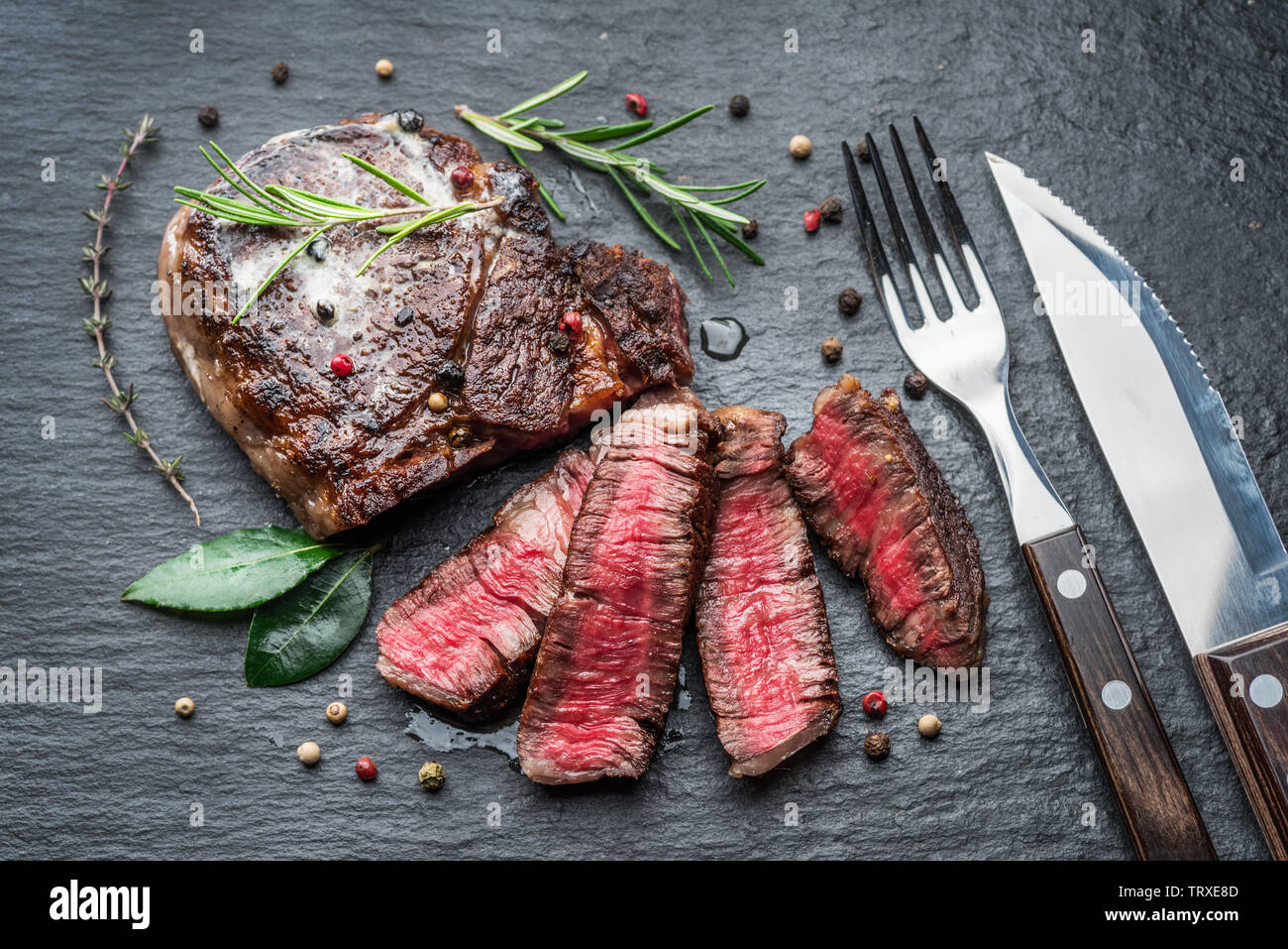 Medium rare Ribeye steak with herbs on graphite board Stock Photo - Alamy