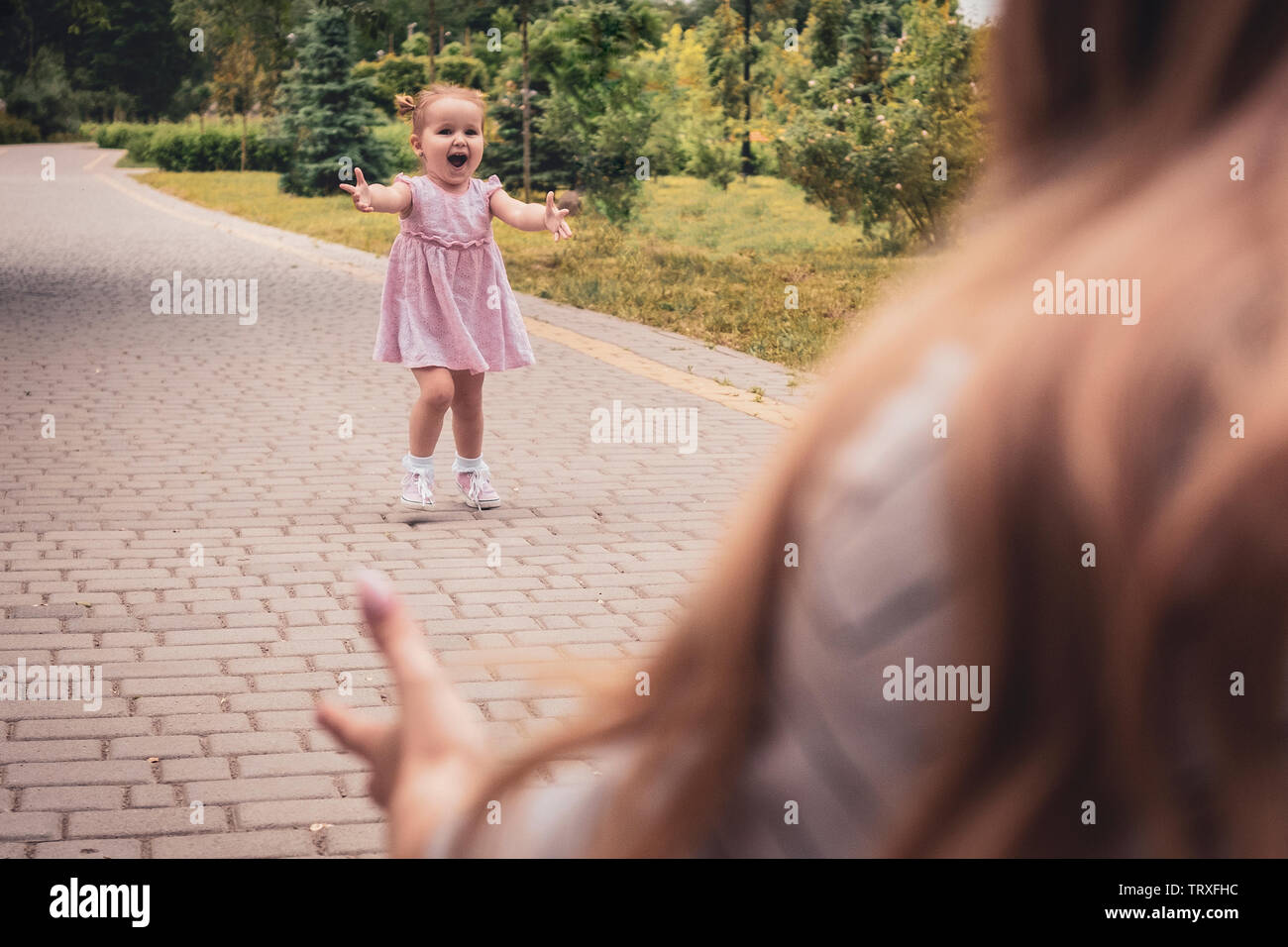 Little girl running towards her loving mother standing with open arms ...