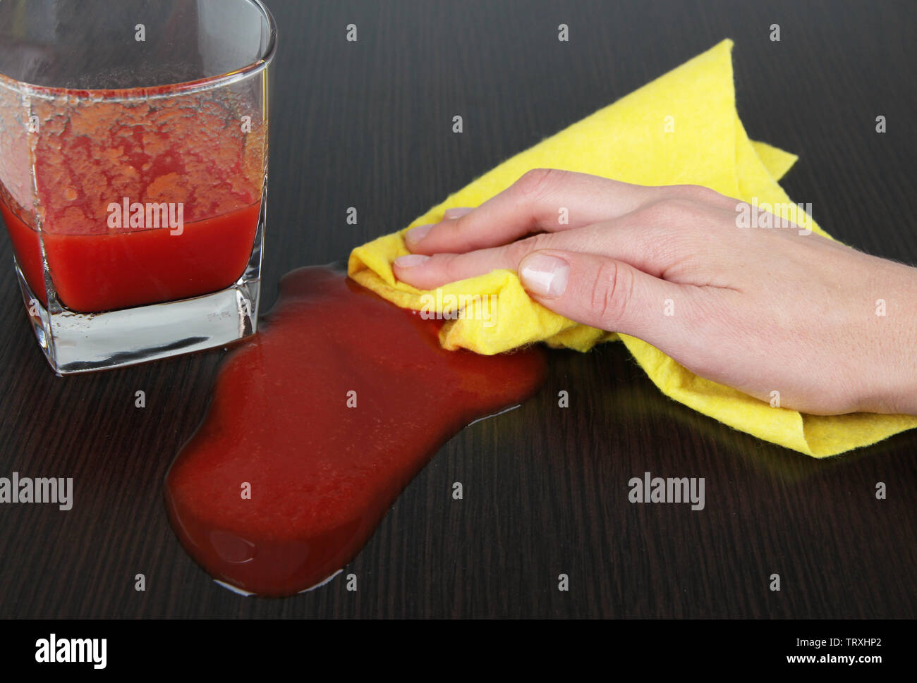Hand wiping wooden surface with yellow rag and glass of juice Stock ...