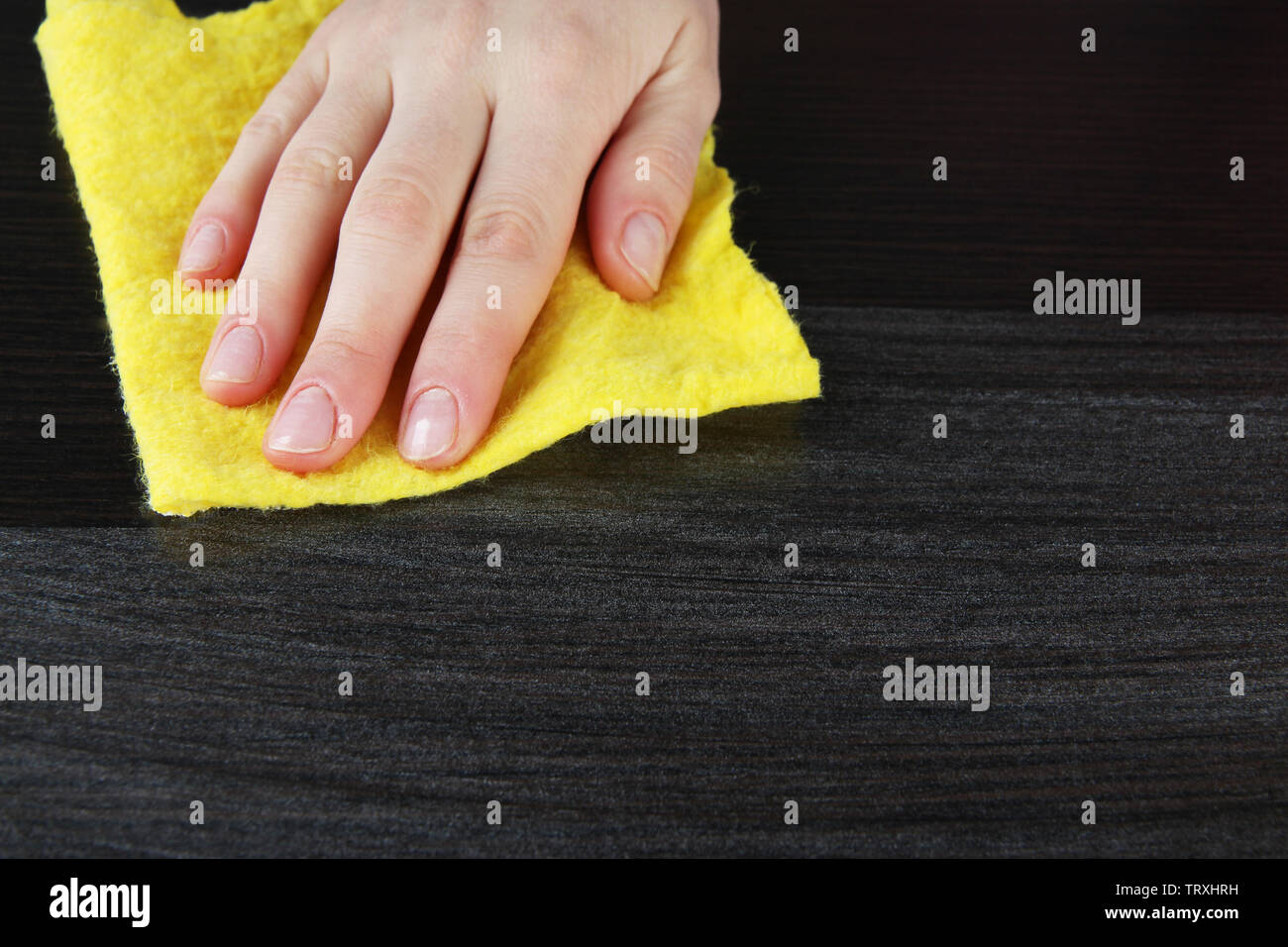 Hand wiping wooden surface with yellow rag Stock Photo - Alamy