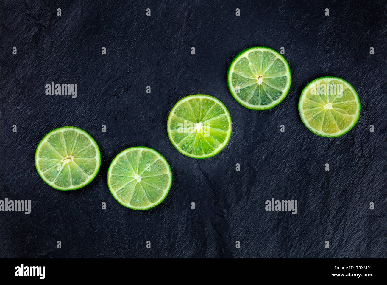 Lime slices, shot from above on a black background with copy space ...
