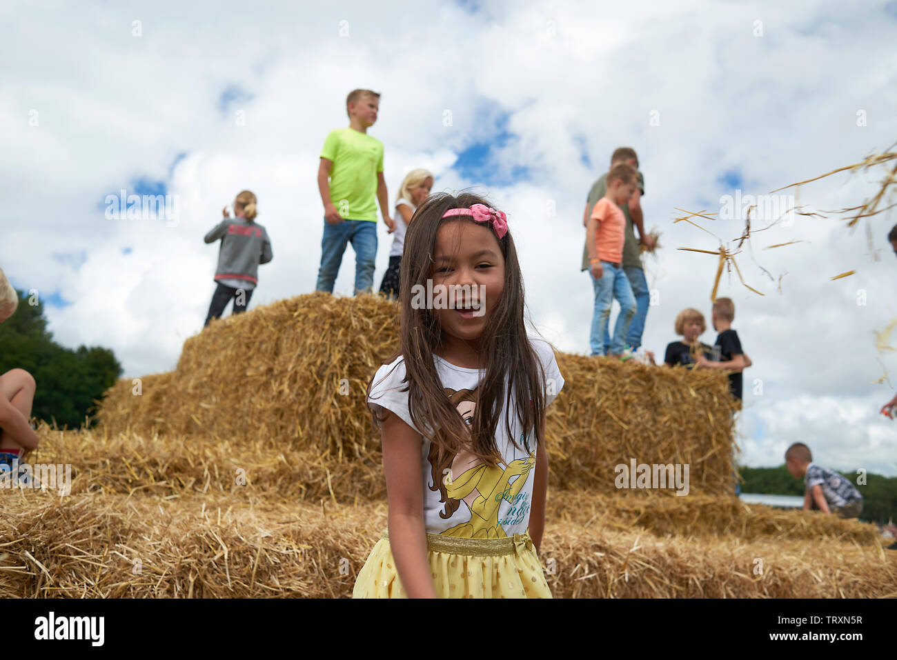 Kids playing on top of a haystack and throwing around the hay in summer ...