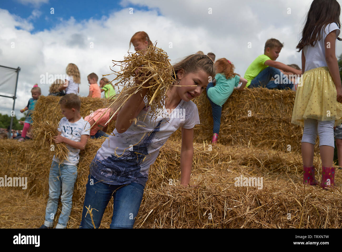 Kids playing on top of a haystack and throwing around the hay in summer ...
