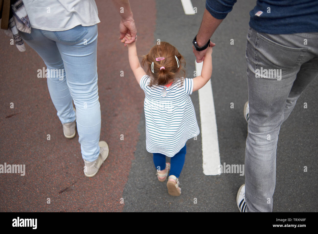 Married couple walking hand in hand with their first born child helping ...