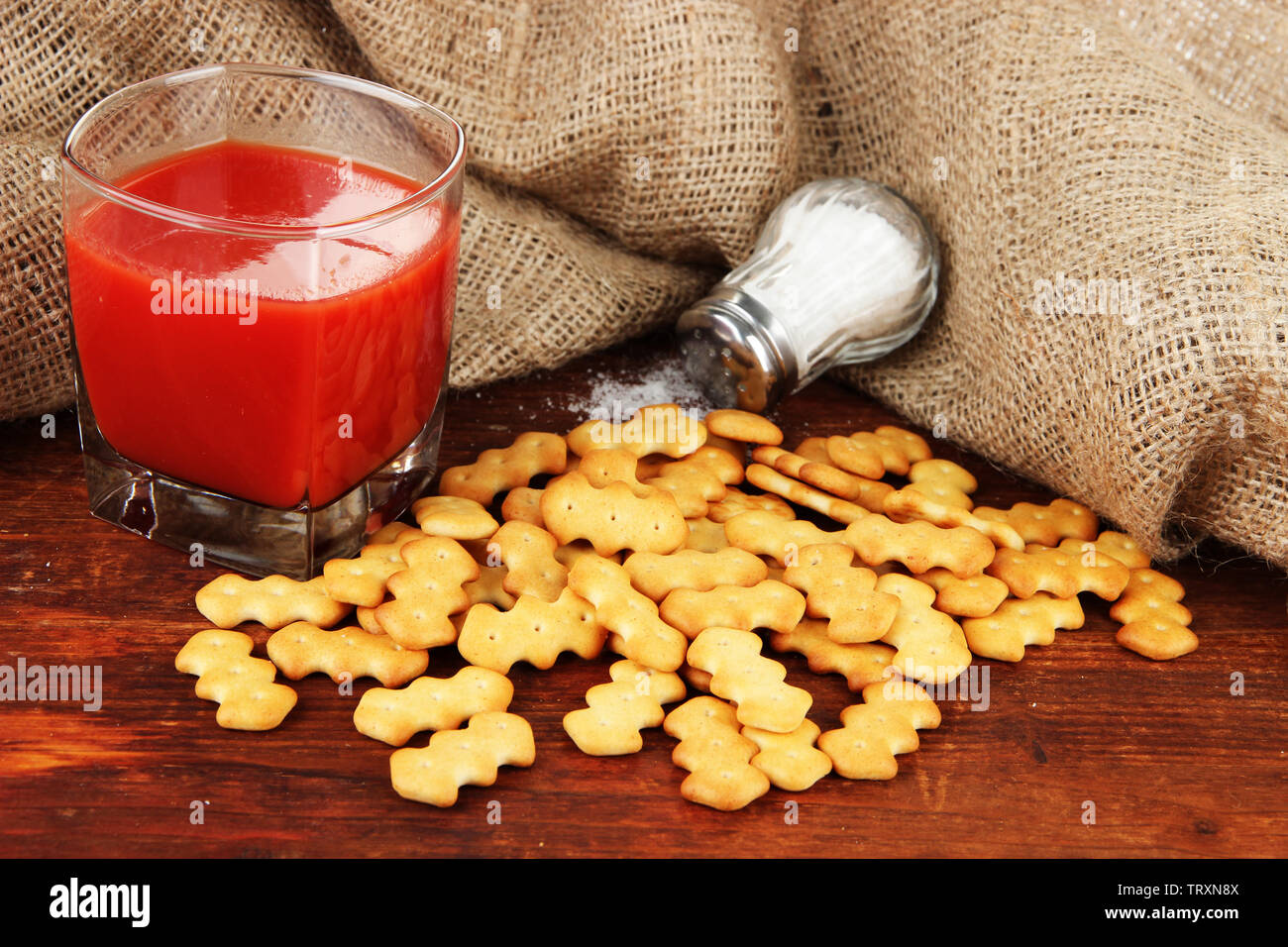Delicious crackers with salt and tomato juice on wooden table on ...