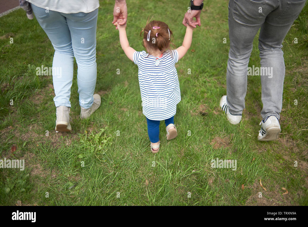 Married couple walking hand in hand with their first born child helping ...