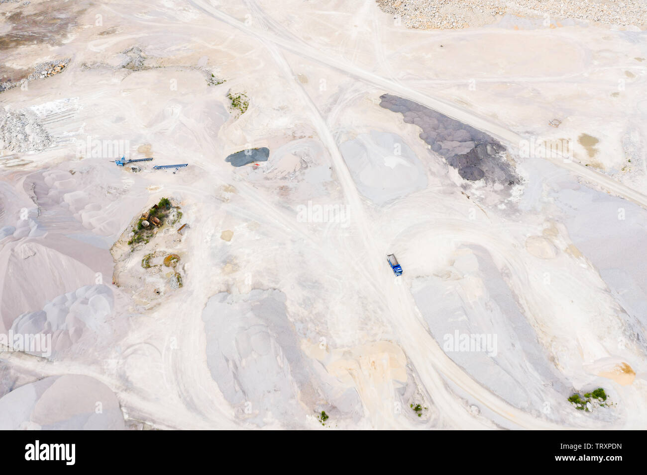 Aerial of bare and desolate stone quarry landscape. A truck is visible ...