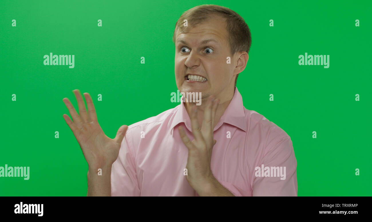 Angry aggressive handsome young man in pink shirt nervous and can not ...